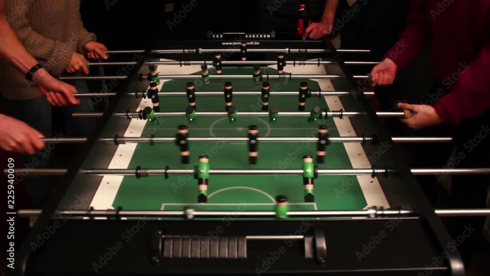 Four people playing table football / table soccer / foosball. The ...