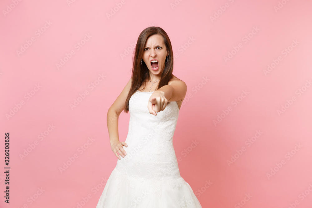 Portrait of strict angry bride woman in white wedding dress swearing ...