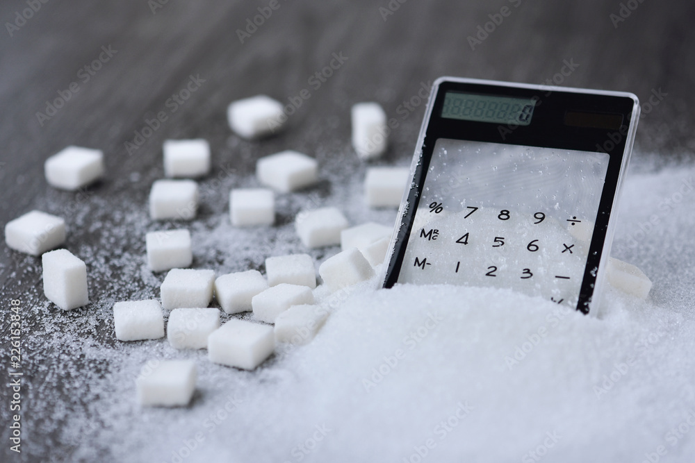 Clear calculator on white granulation sugar and cube sugar background ...