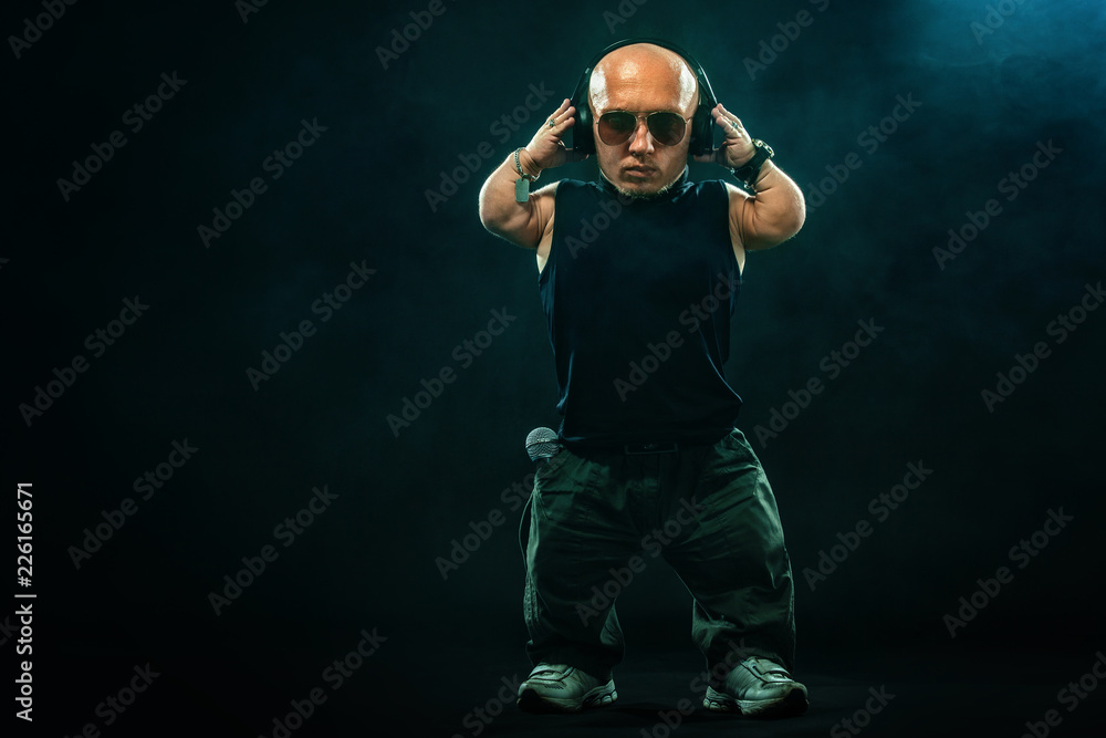 Portrait of stylish midget MC in with headphones and sunglasses posing ...