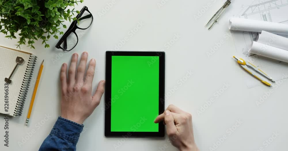 Top view on the male hands scrolling and tapping on the green screen of ...
