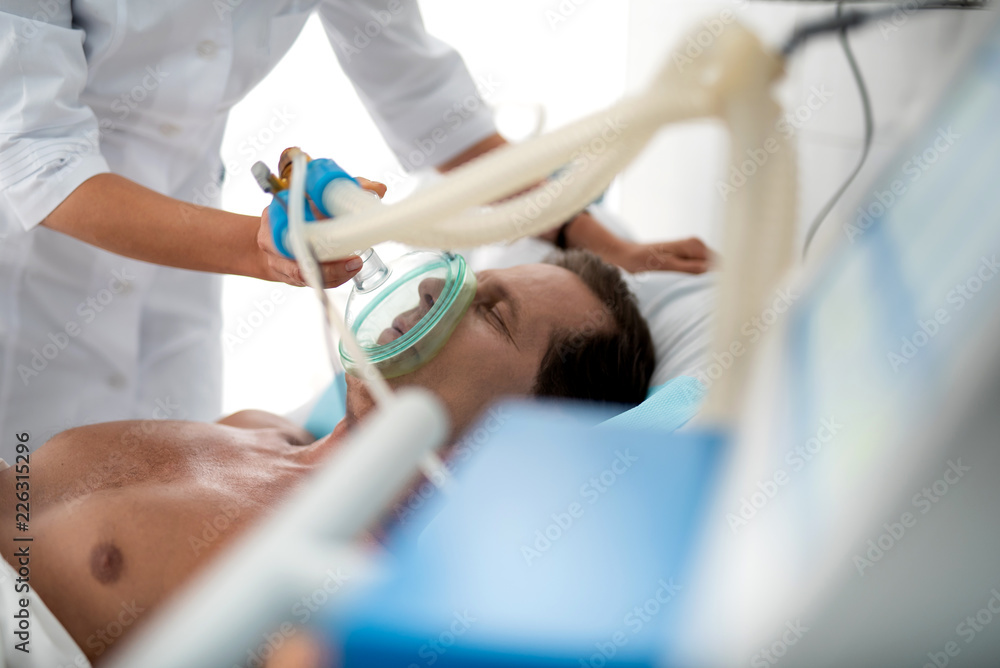 Close up portrait of middle aged man with oxygen mask lying in bed ...