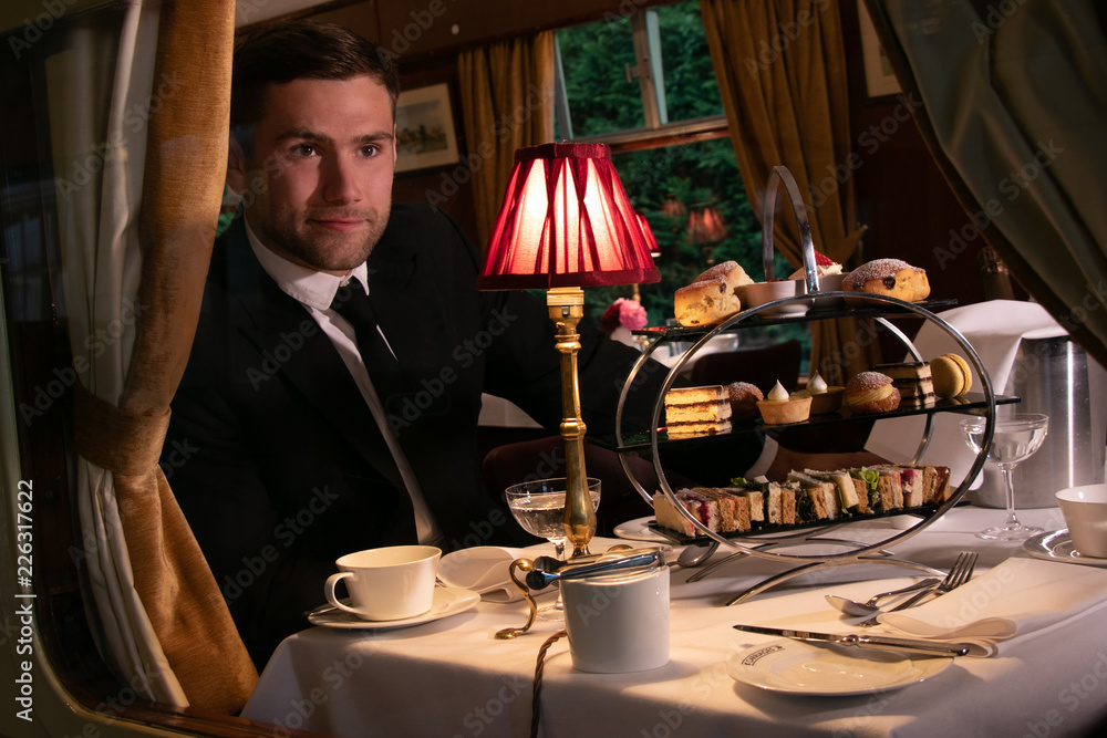 Good looking man in suit enjoying afternoon tea in vintage train ...