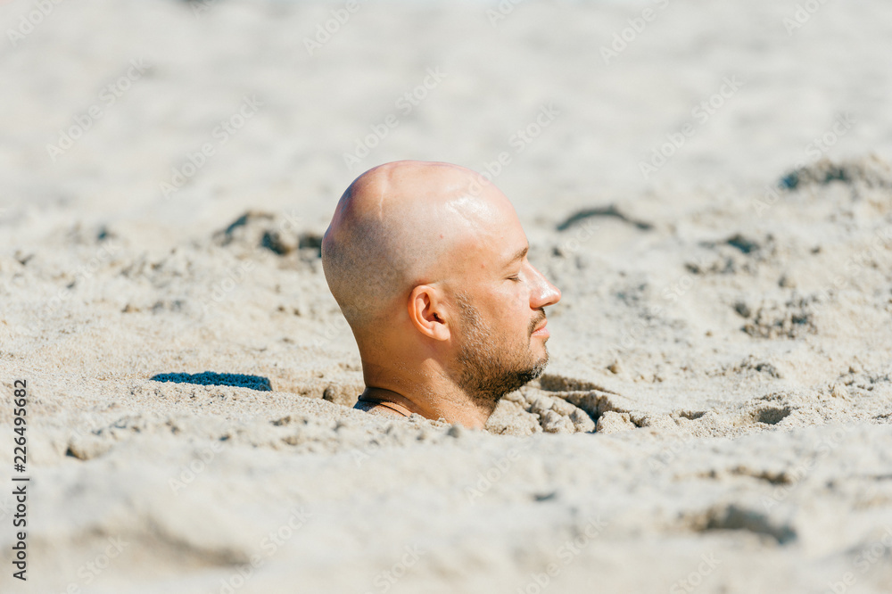 Fotka „Male bald head above sand. Man buried alive in desert. Punished ...