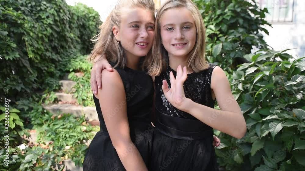 Pretty identical twins girls in the black dress posing on camera ...