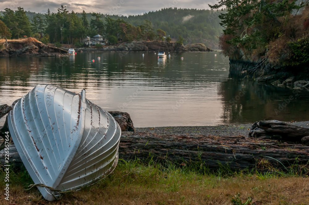 upside down row boat lying on driftwood on pebble beach on Pender ...