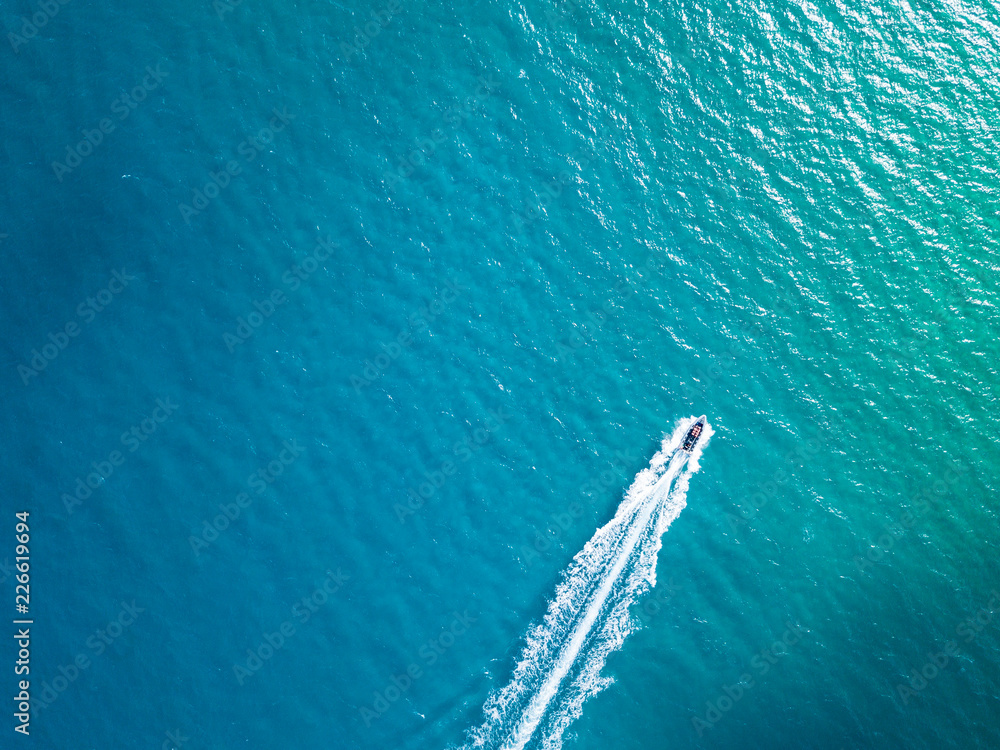 Bird's eye aerial top view of a boat cruising in crystal clear ...
