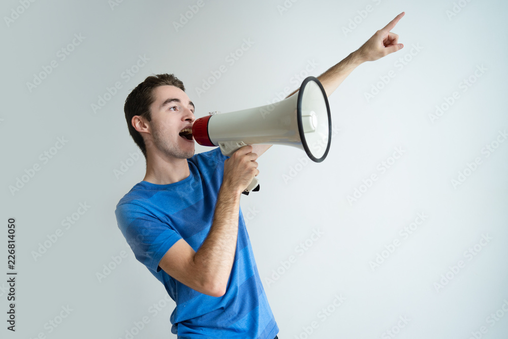 Serious man shouting into megaphone and pointing away. Young guy ...
