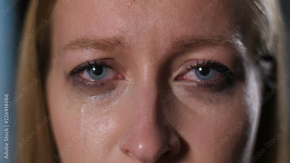 Closeup portrait of adult woman with deep sorrowful blue eyes staring ...