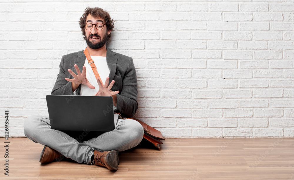 young man sitting on the floor looking scared, frightened and horrified ...