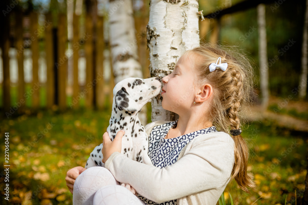 Cute girl kissing her puppy, doggy on the wood fence background.Happy ...