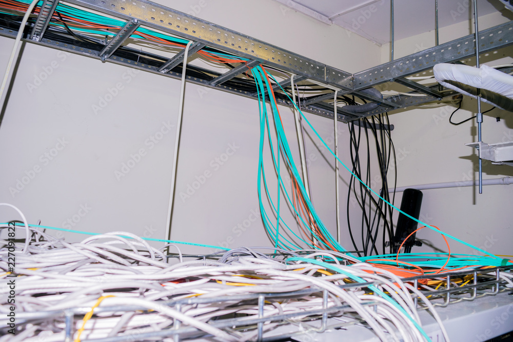 Messy wires are tangled among themselves on the suspended ceiling of ...