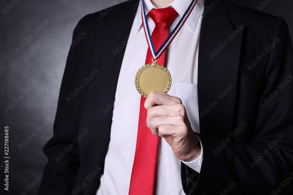 Elegant man in black suit holding and showing a gold medal Stock Photo ...