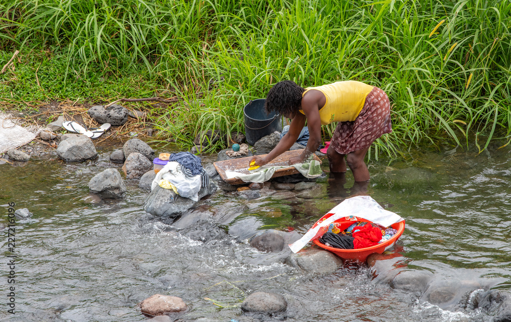 Villager washing clothes in the river. Travel to Sao Tome and Principe ...