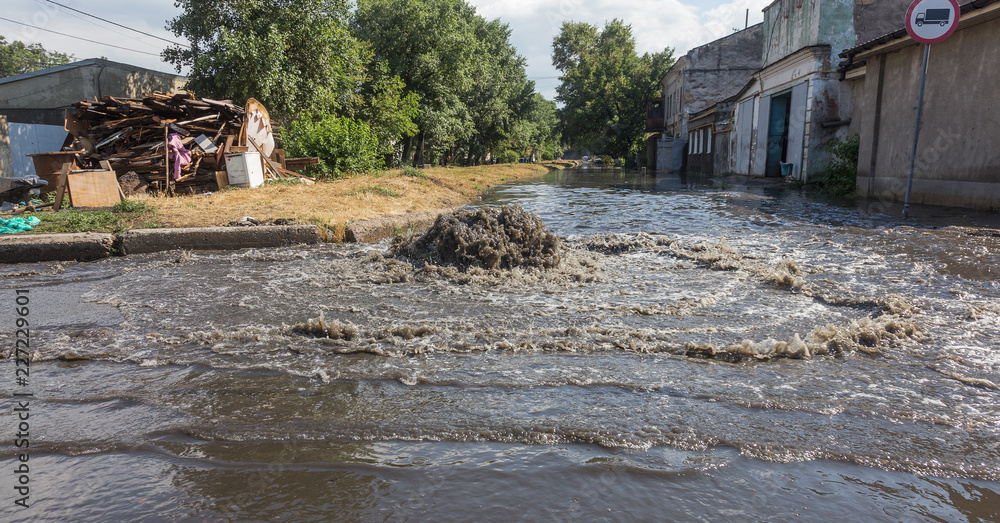 Water flows out of road sewage hatch. Drainage fountain of sewage ...