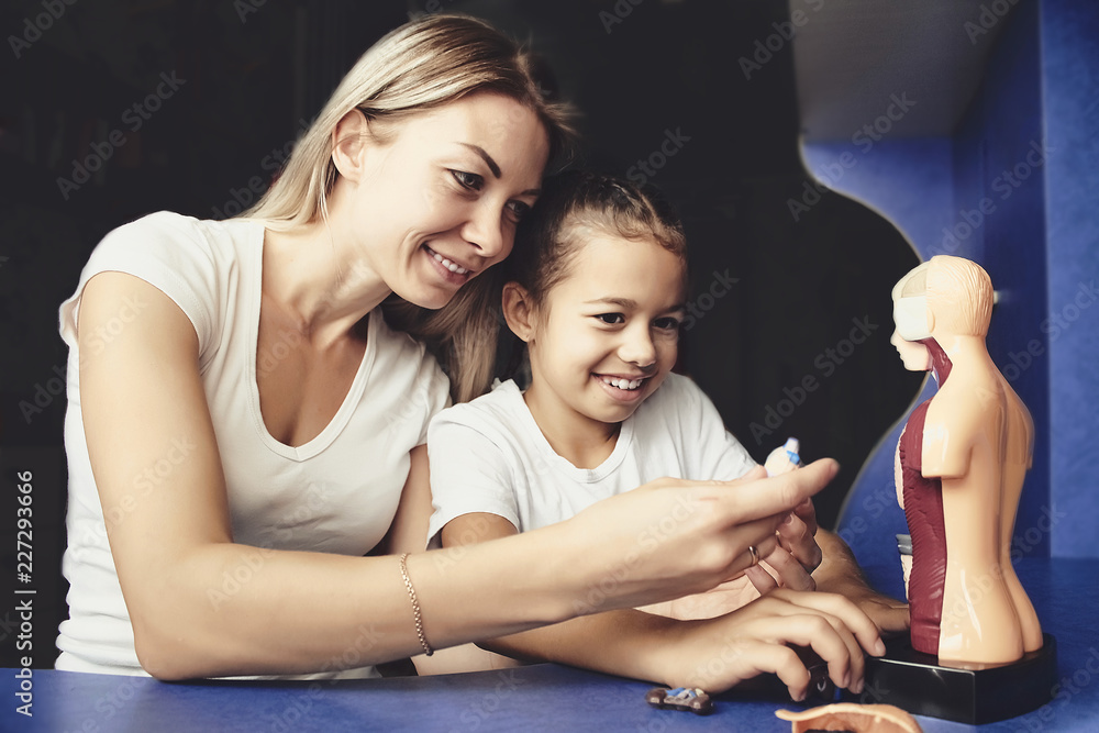 Female private tutor helping young student with homework at bioilogy ...