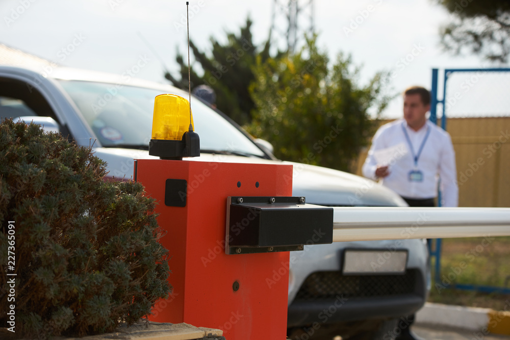 Security man checking car at the protective barrier and security office ...