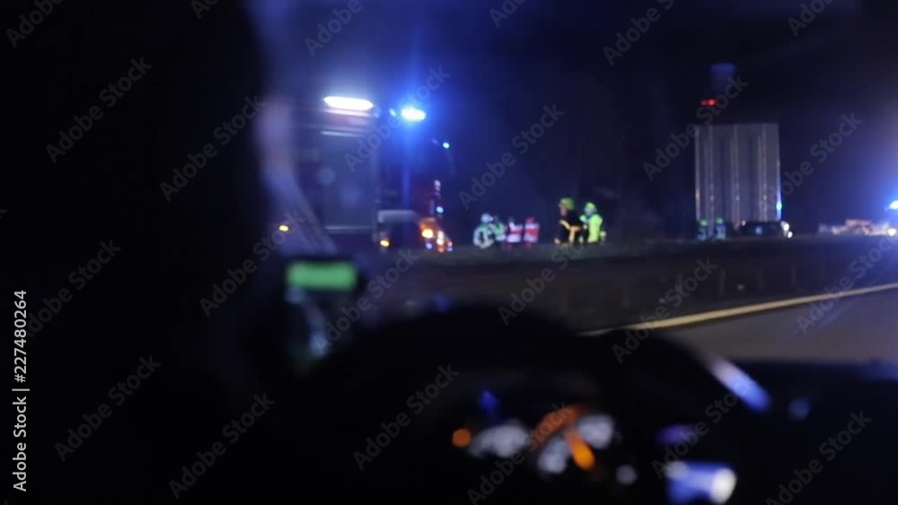 Driving by a car crash on highway at night. View from inside the car ...