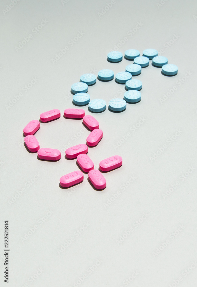 Pills arranged in shape of male and female symbols on white background ...