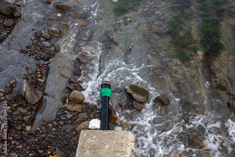 Contaminated water, sewage waste is drained through pipe into sea on an ...