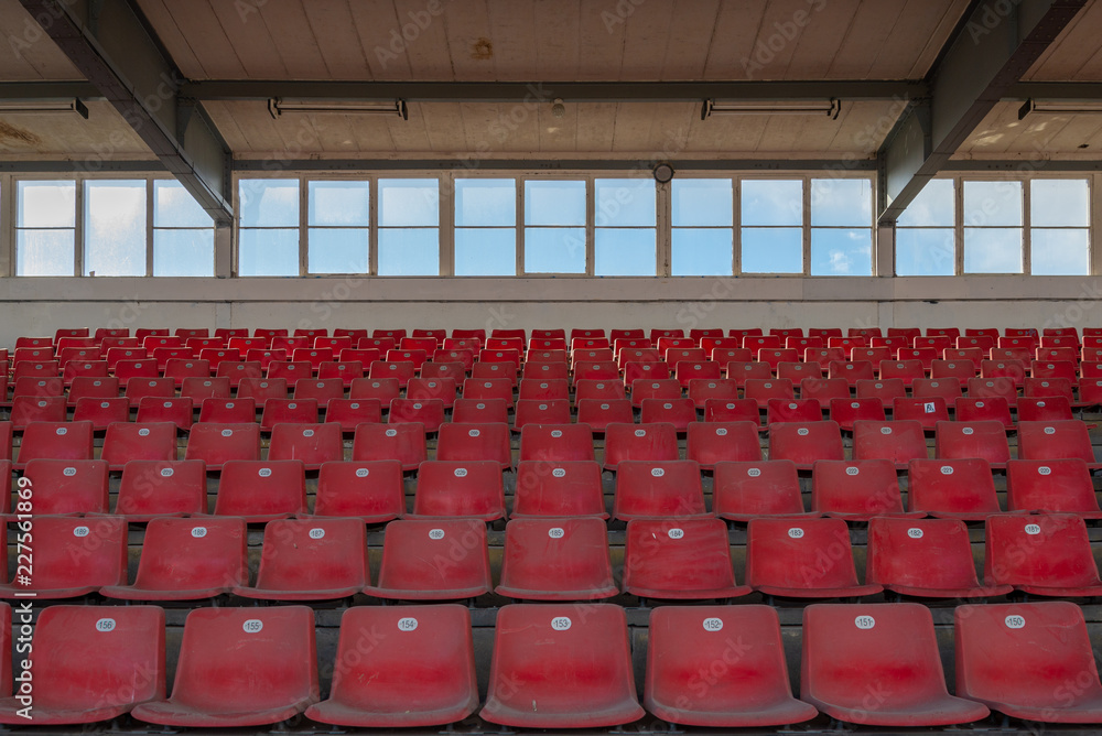 Front view row of red plastic seats on rough concrete step floor in old ...