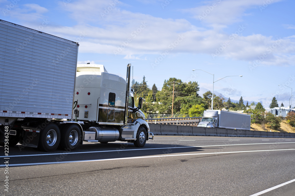 Big rigs semi trucks with semi trailers running towards each other in ...