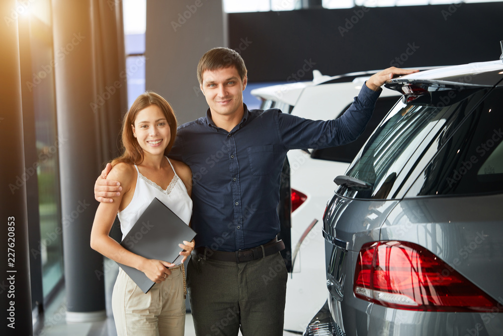 Making a decision. Beautiful young couple choosing a new car at the car ...