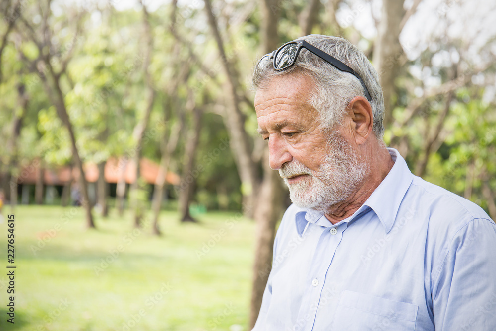 Portrait of sad senior caucasian old man thinking in the park outdoors ...