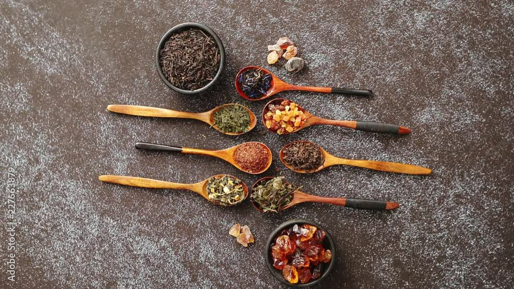 Spoons with different types of dry tea leaves on rusty dark background ...