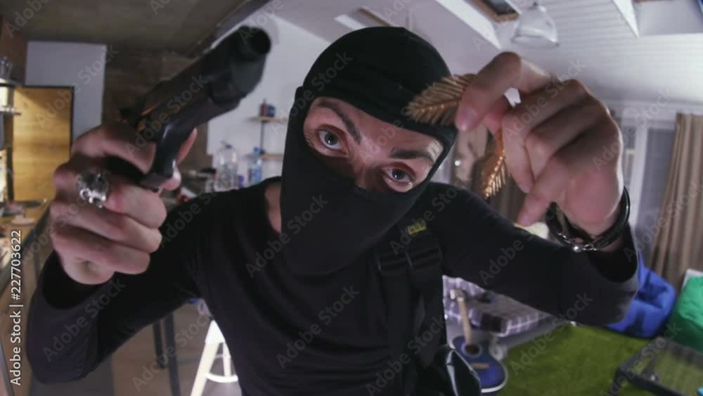 Caucasian bandit in black balaclava showing gold earrings into hidden ...