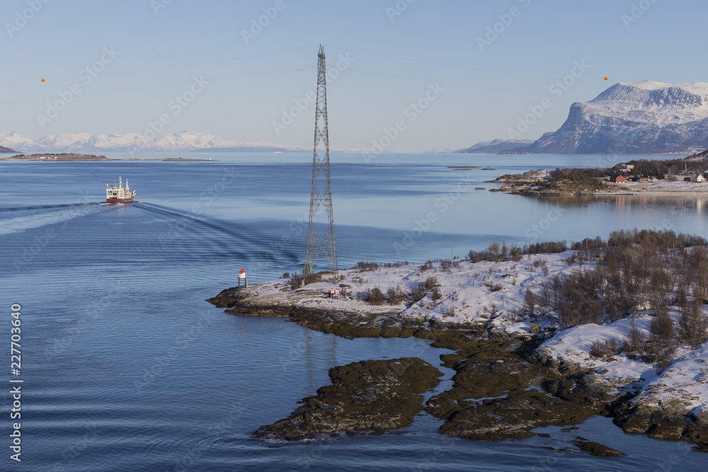 Boat passing the Tjeldsundet strait which separates the mainland from ...