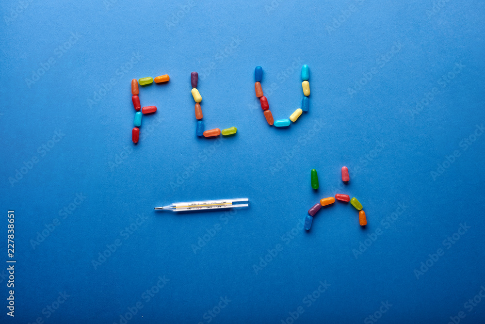 The word "flu" is laid out from multi-colored tablets, vitamins, jelly ...