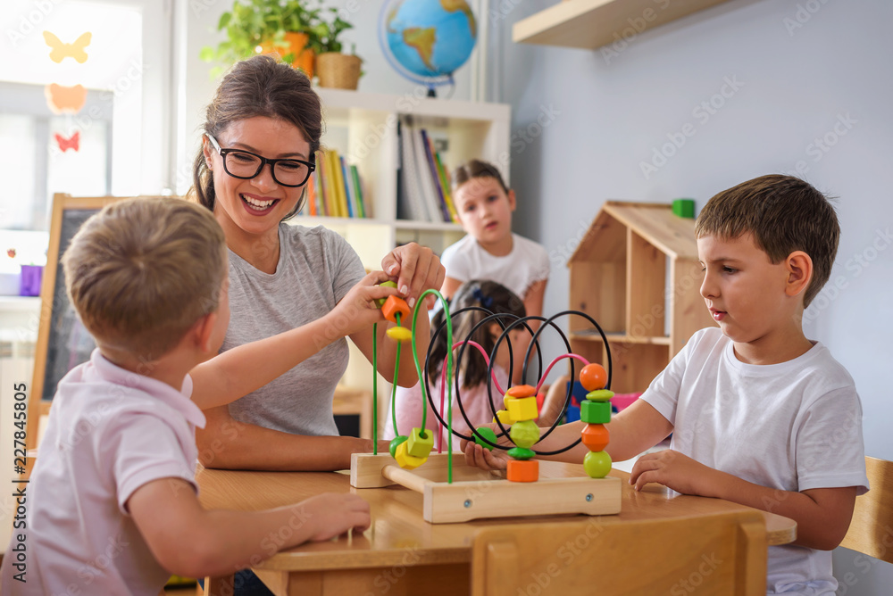 Preschool teacher with children playing with colorful wooden didactic ...