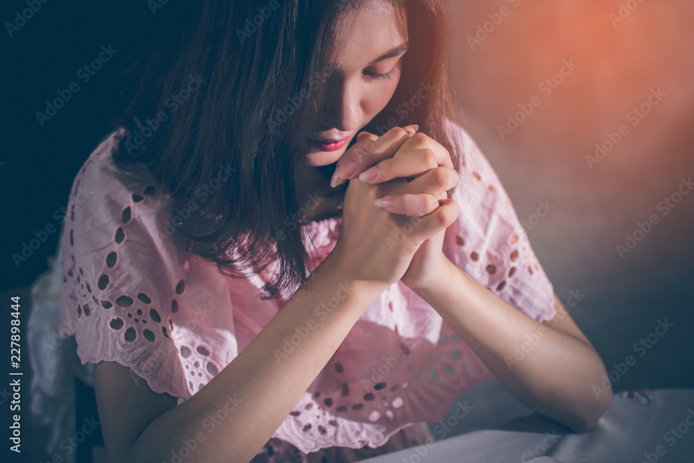 Asian girl wearing a pink dress. Her eyes closed and hands in prayer ...