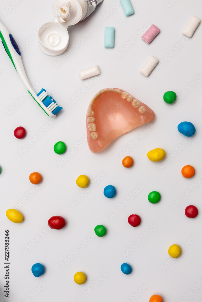 different colors sweets bonbons and chewing gum, dental prothesis ...