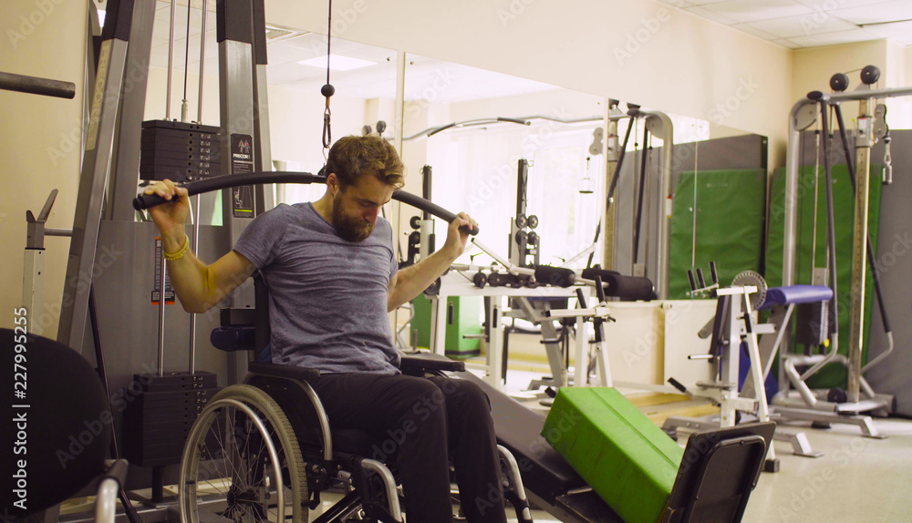 Young disabled man in wheelchair doing strength exercises for hands at ...