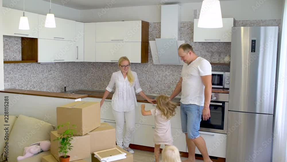 Young happy family moving to new apartment. Two little girls running ...