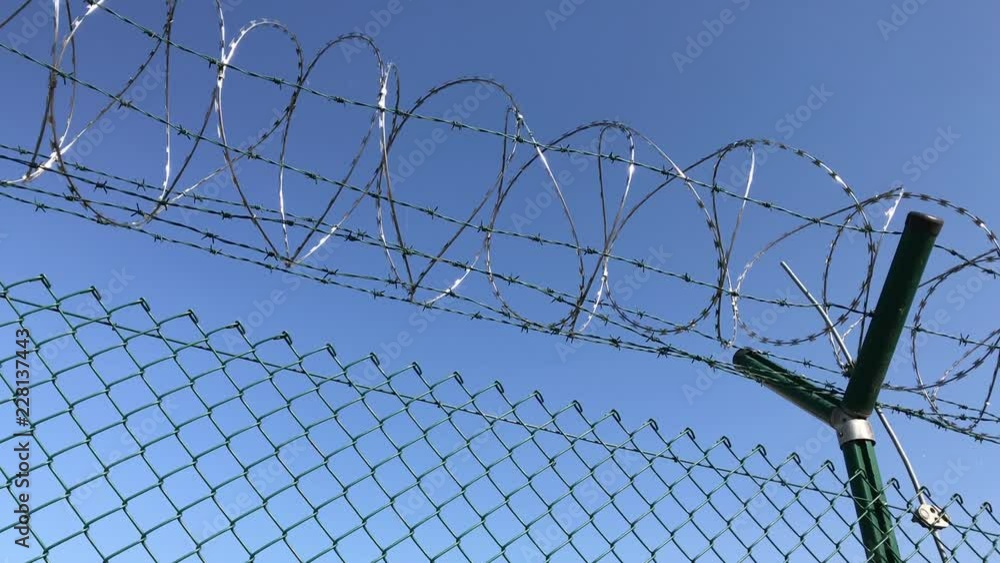 Barbed wire on net fence under blue sky taken close up. Protection ...