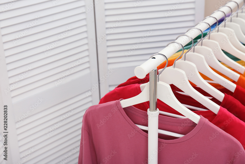 Rack with bright clothes in room. Rainbow colors Stock Photo | Adobe Stock
