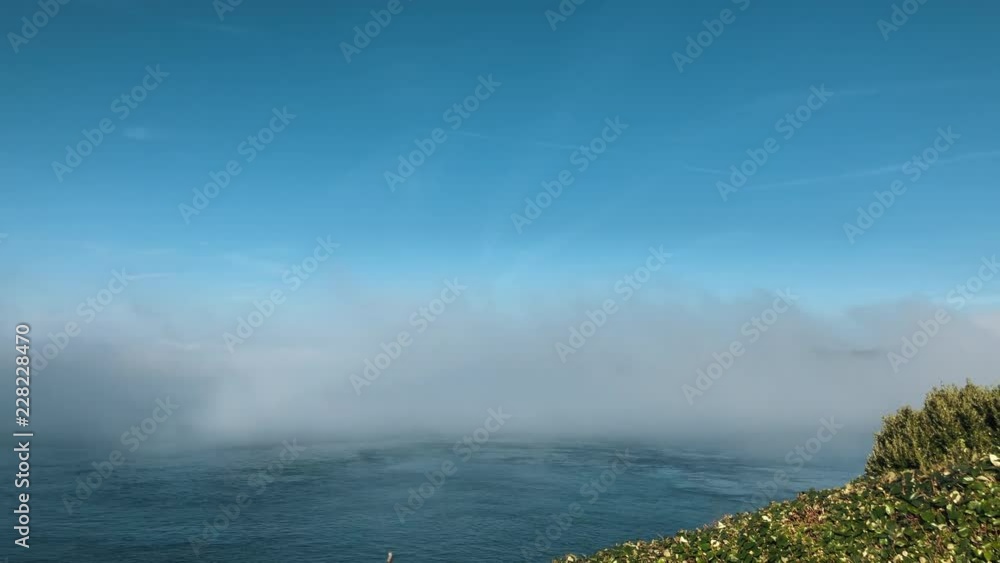 Fog forming over sea, camera pans right showing island shrouded in fog ...