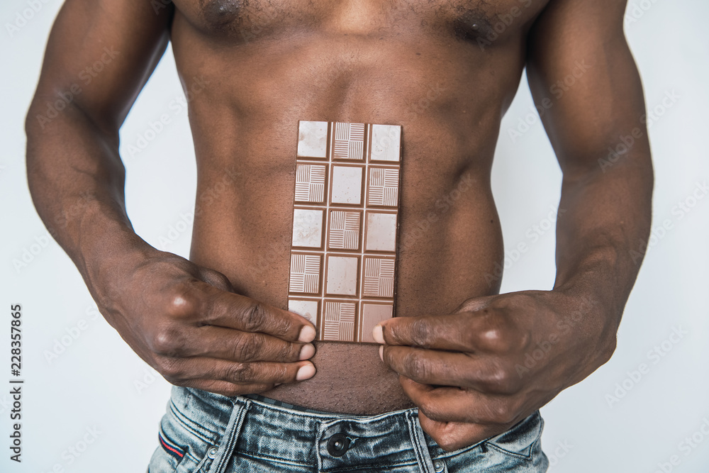 Crop black shirtless man with bar of chocolate Stock Photo | Adobe Stock