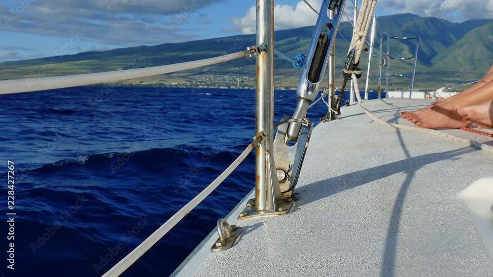 This is 4k video of people's feet on a sailboat sailing off the coast ...