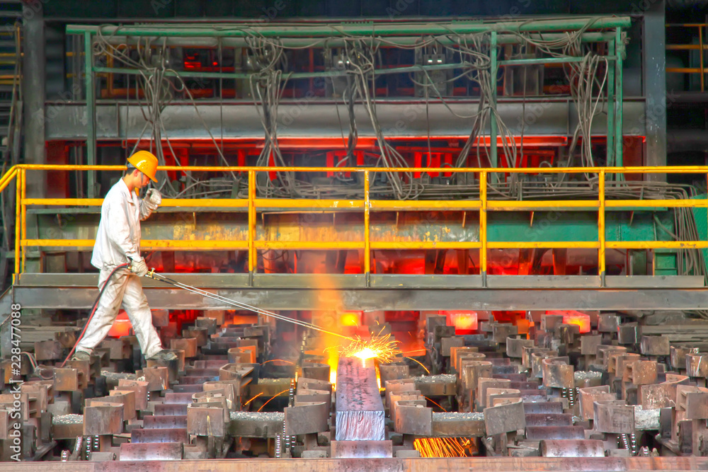 Workers cutting steel ingot behind the continuous casting machine in ...