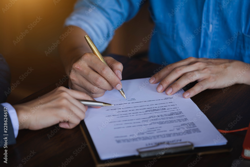 Close up of customer signing a paper document for buying house. Estate ...