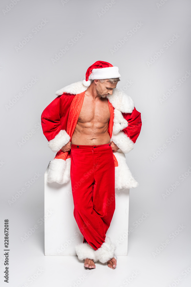 sexy barefoot man in santa costume posing in studio and looking away on ...