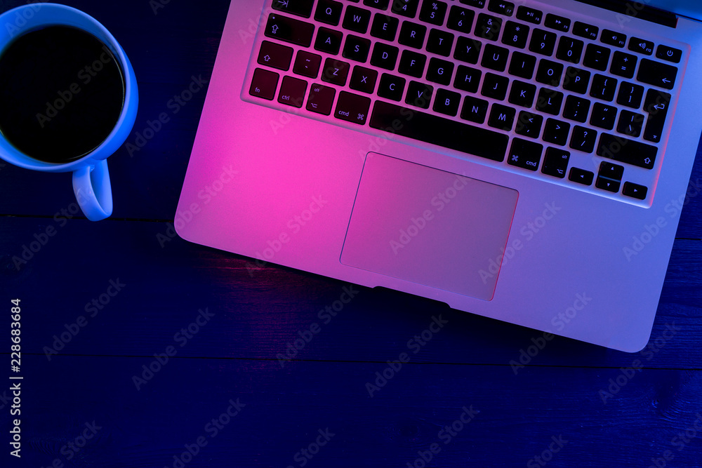 Laptop computer keyboard wood office desk table at night with lights ...