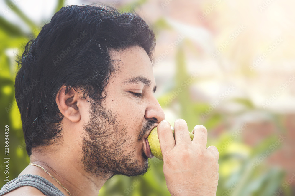 Foto de Indian man eating mango. do Stock | Adobe Stock