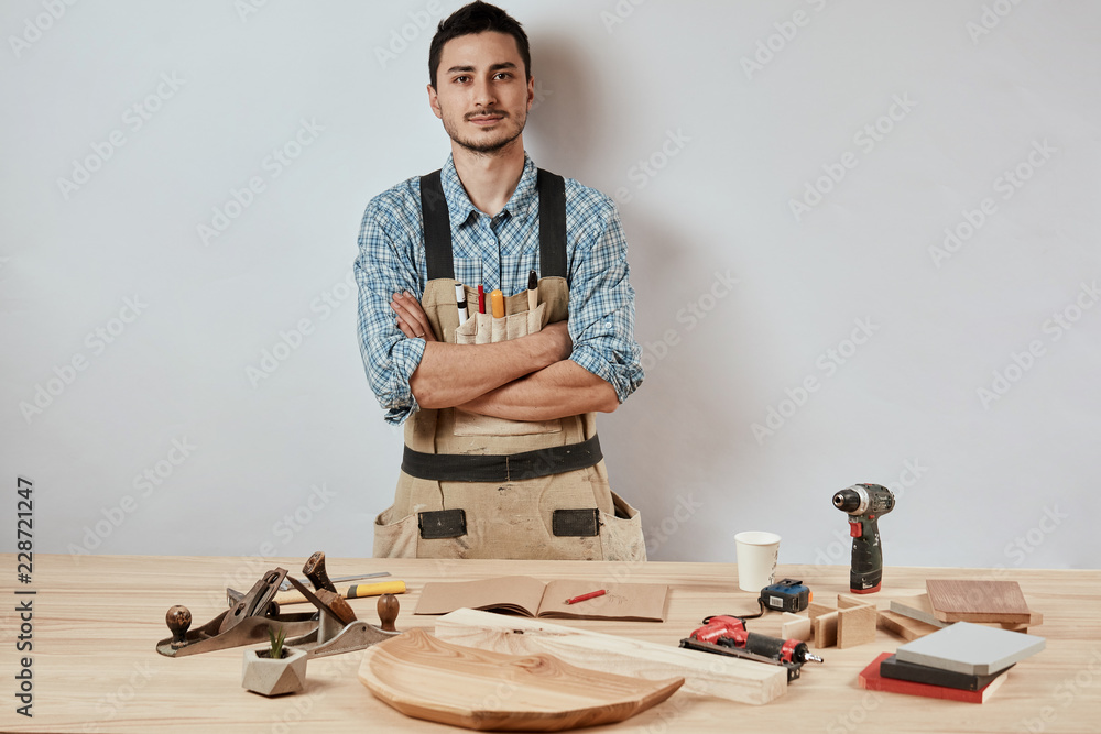 Friendly looking woodwork master in workwear and apron, looking at ...