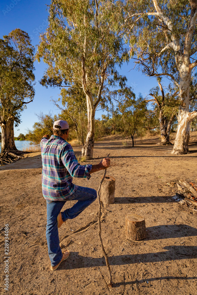 Indigenous Australian man standing on river bank in a traditional pose ...