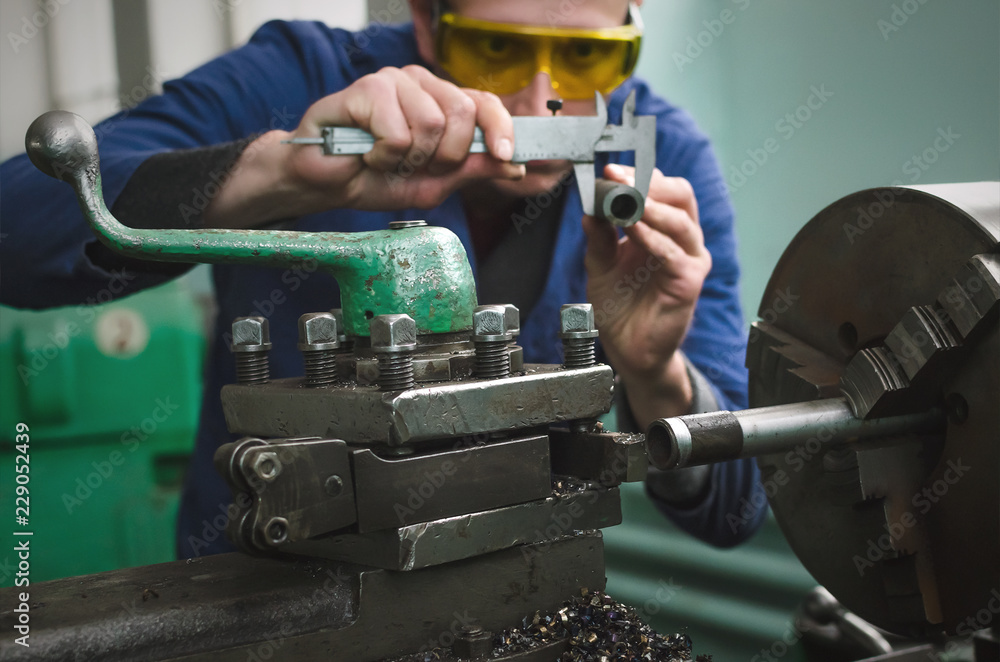 Foto de Turner is working on a lathe machine in a factory. Worker is ...